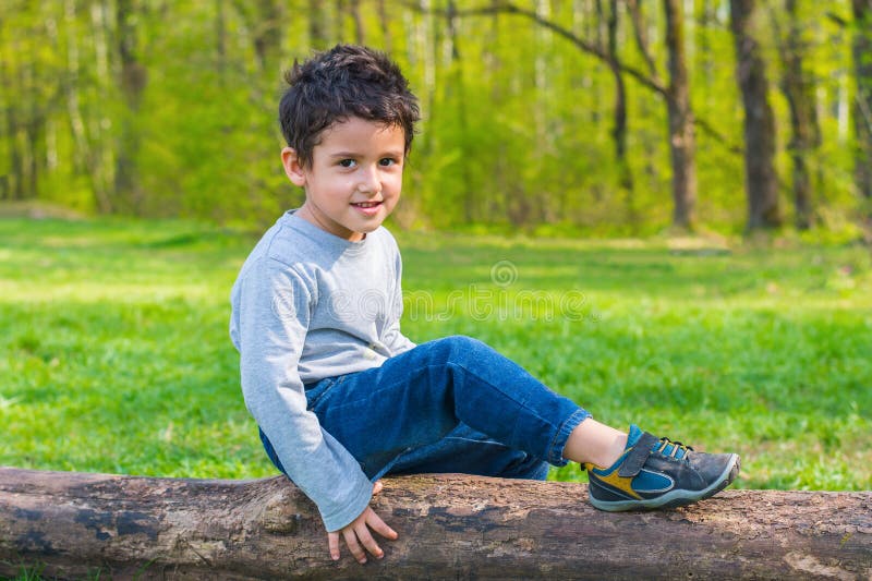 Joyful Boy Sitting on a Log in the Woods Stock Image - Image of smile ...