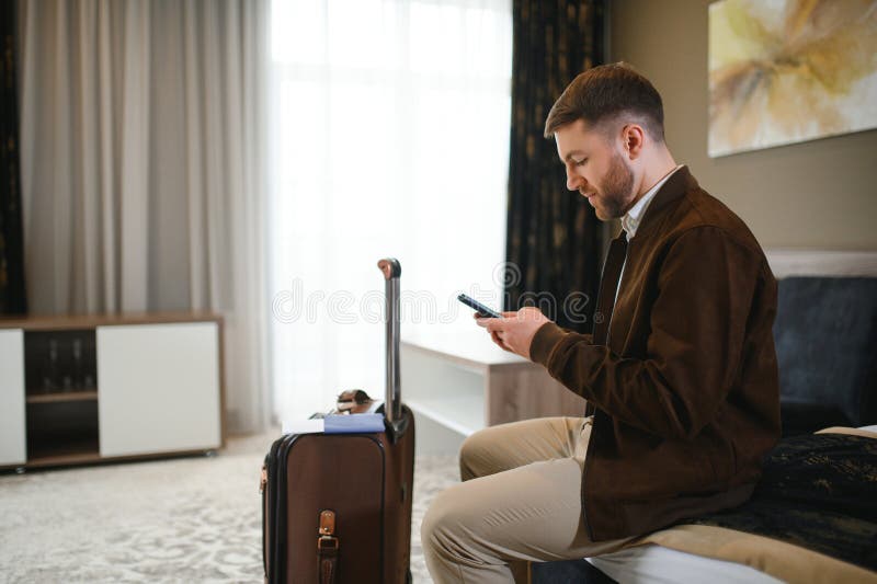Cheerful Businessman Using Phone Sitting in Hotel Room on Business Trip ...