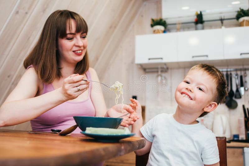 Cheerful Child Eating Pasta in the Kitchen with Mom Stock Image - Image ...
