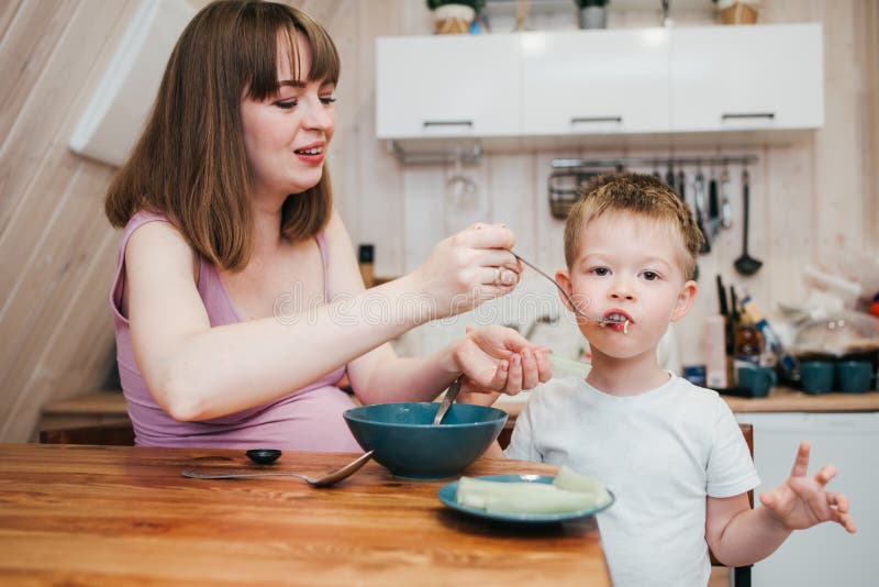 Cheerful Child Eating Pasta in the Kitchen with Mom Stock Image - Image ...