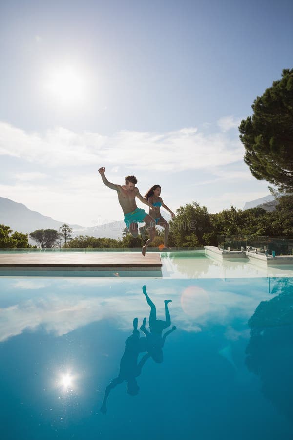 Cheerful Couple Jumping into Swimming Pool Stock Photo - Image of ...