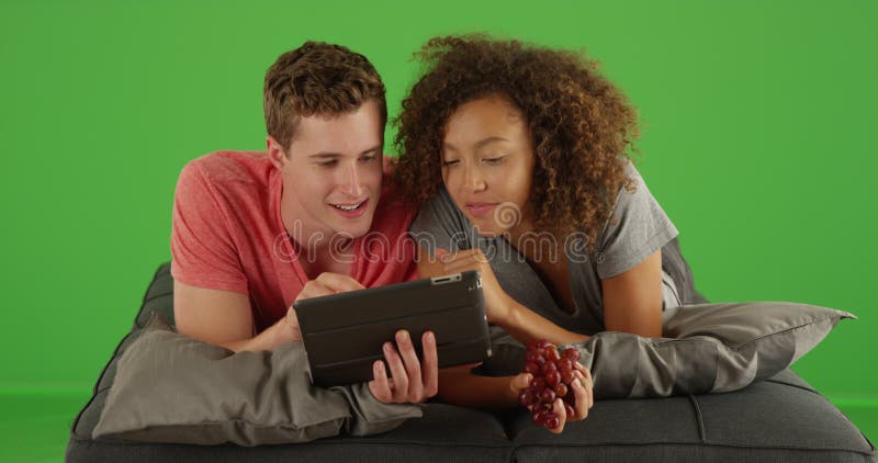 Cheerful Couple Using Digital Tablet on Couch on Green Screen Stock ...
