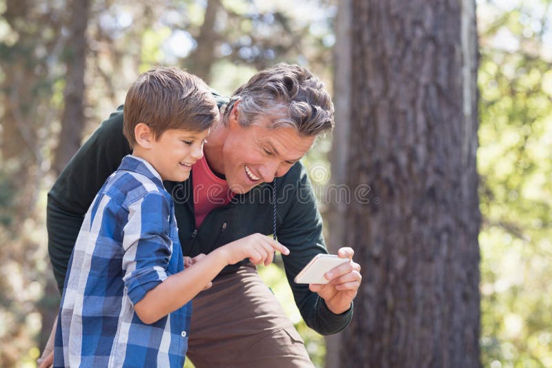 Cheerful Father and Son Using Mobile Phone in Forest Stock Photo ...