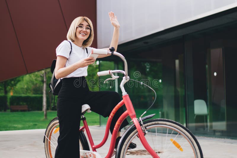 Cheerful Female Cyclist Using Smartphone and Waving Hand Stock Photo ...