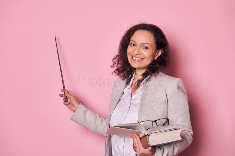 Cheerful Female Teacher Pointing with Pointer at Pink Background while ...