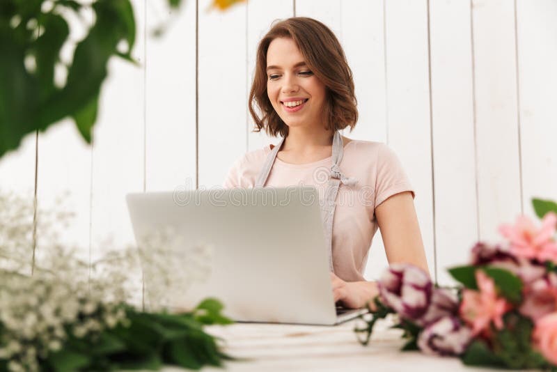 Cheerful Florist Lady Standing with Flowers Using Laptop Computer ...