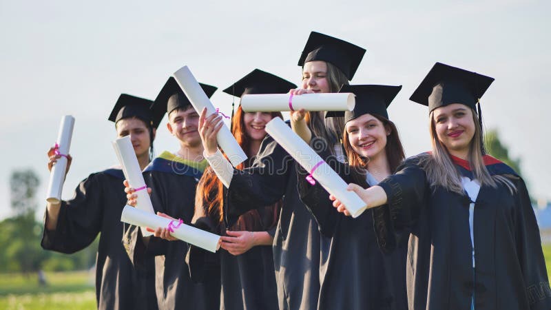Cheerful Graduates Pose with Raised Diplomas on a Sunny Day. Stock ...