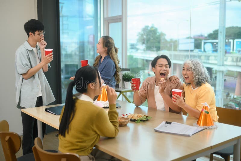 Cheerful Group of Colleagues Enjoying Snacks and Drinks during a Lively ...