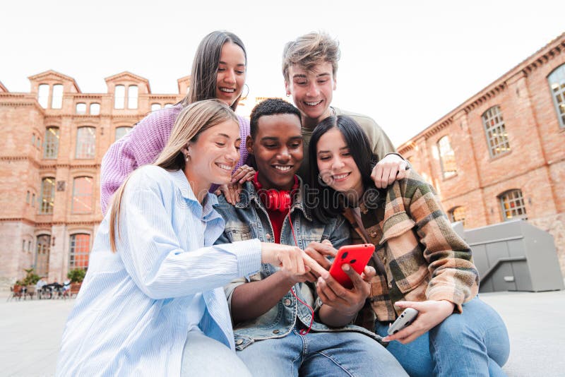Cheerful Group of Students Browsing with a Smartphone, Sharing Laughter ...