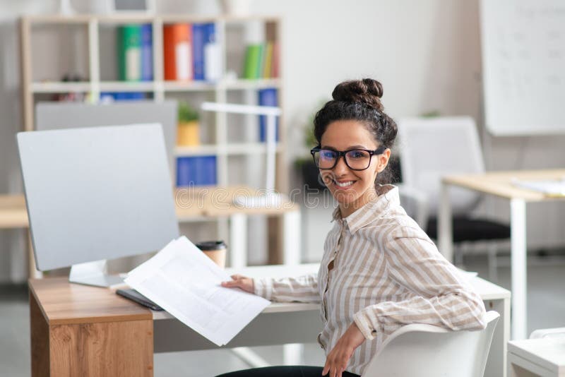 Cheerful Latin Female General Manager Checking Reports in Modern Office ...
