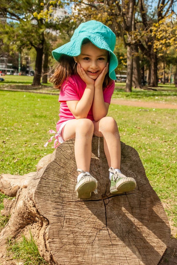 Cheerful Little Girl Sitting on a Tree in the Park Stock Image - Image ...