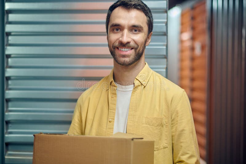 Cheerful Loader Holding a Cardboard Box and Looking Ahead Stock Image ...