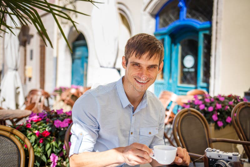 Cheerful Man Enjoying Coffee at a Parisian Cafe with Flowers in Spring ...