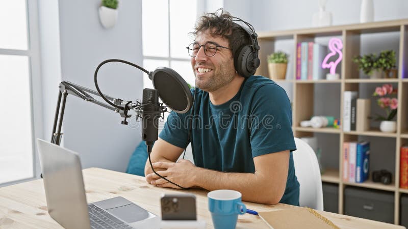 A Cheerful Man with Headphones Speaking into a Microphone in a Bright ...