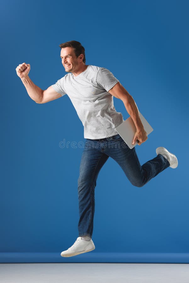 Cheerful Man Holding Laptop and Jumping Stock Image - Image of young ...