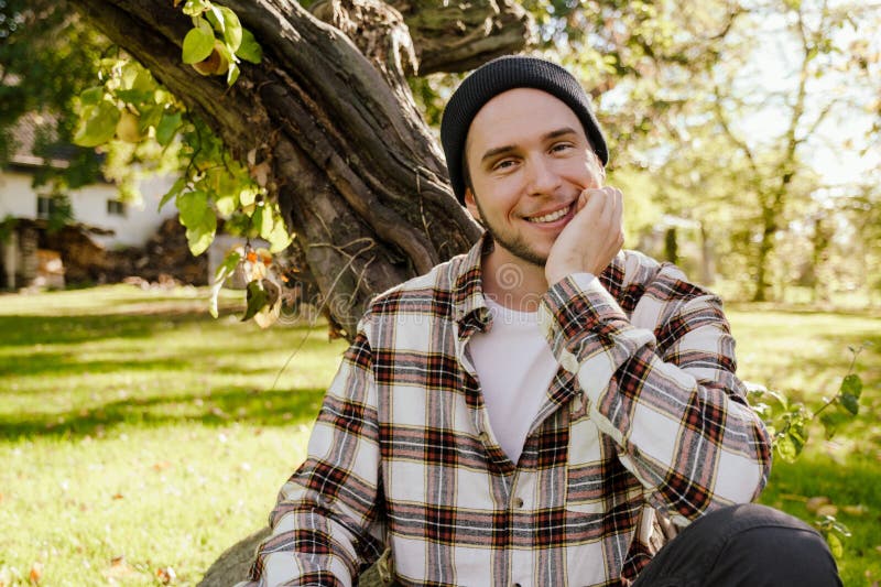 Cheerful Man Sitting Near Tree in Backyard Stock Photo - Image of ...