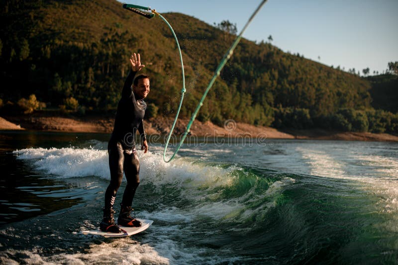 Cheerful Man Throws a Rope and Rides a Wave on a Foil Wakeboard Stock ...