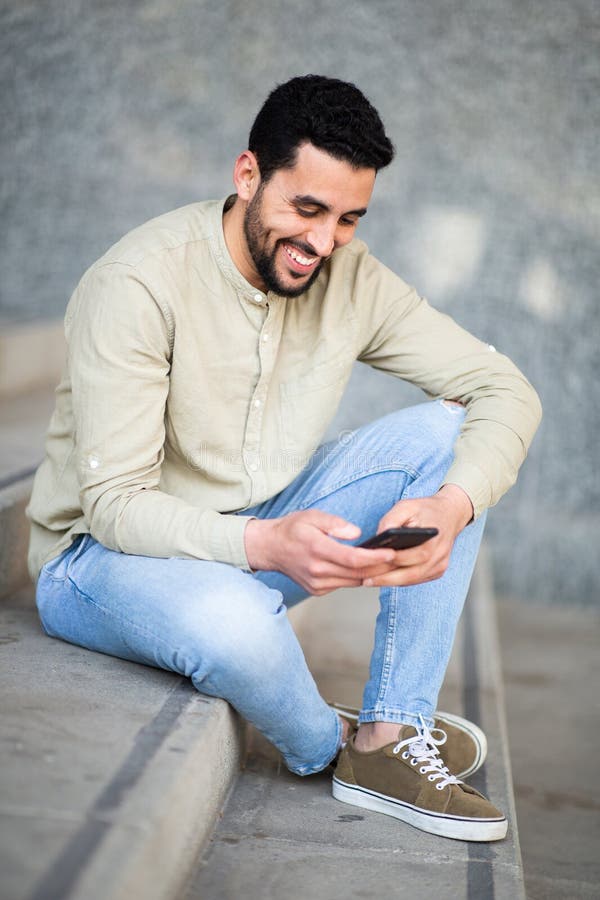 Cheerful Middle Eastern Man Sitting on Steps Using Cell Phone Stock ...
