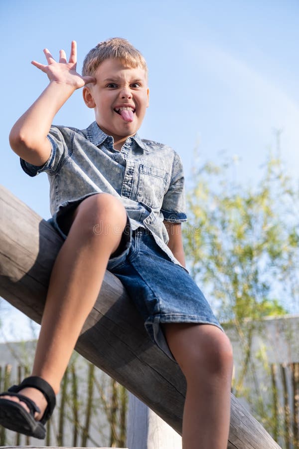 Cheerful and Mischievous Boy Making Faces and Looking at Camera while ...