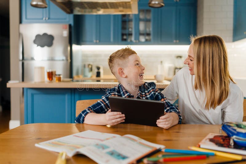 Cheerful Mom and Son Using Tablet Computer while Sitting in Kitchen ...