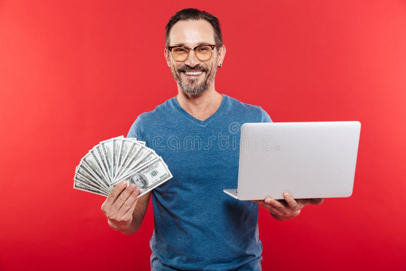Cheerful Positive Man Using Laptop Computer Holding Money. Stock Photo ... Cheerful Positive Man Using Laptop Computer Holding Money. Stock Photo ...