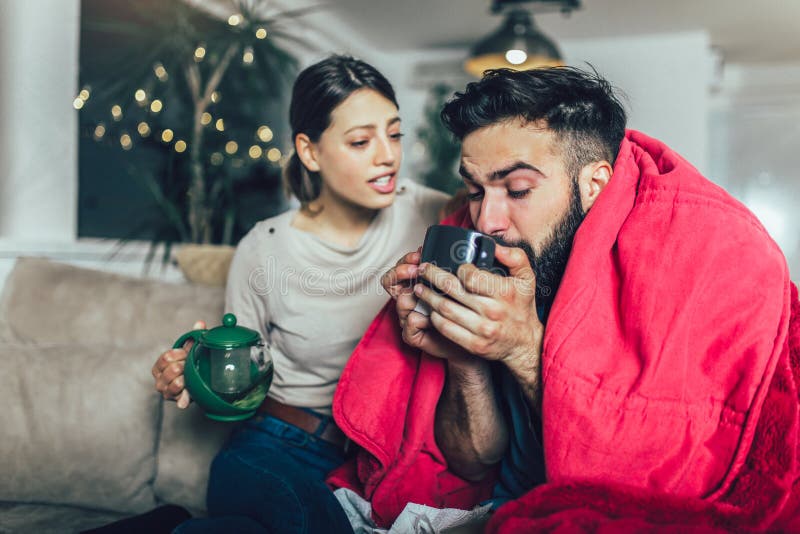 Romantic Couple is Sitting on Sofa Under Cozy Plaid and Smiling. they ...