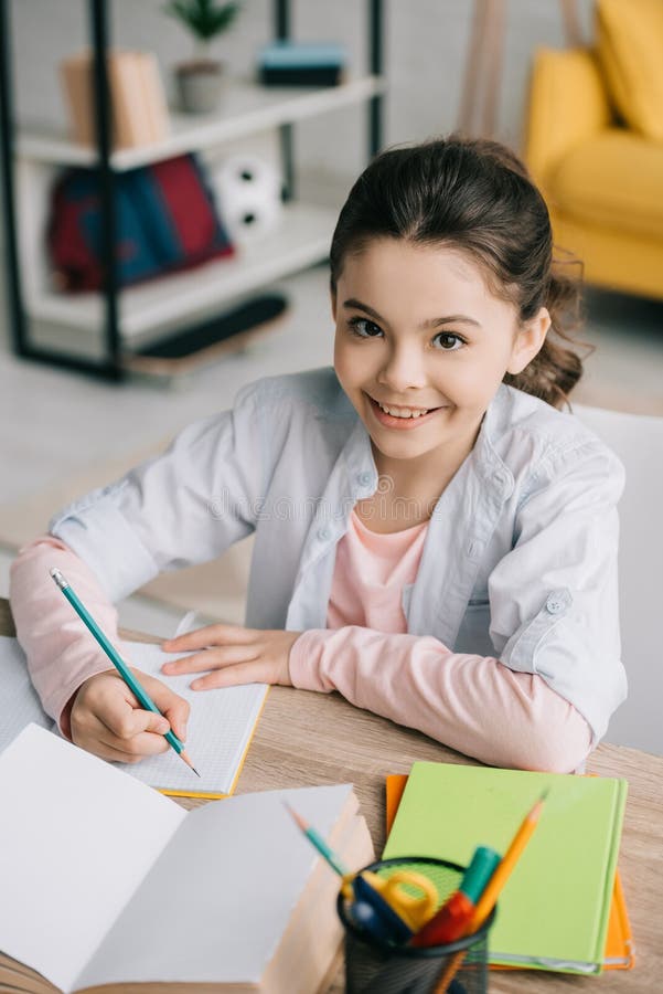 Schoolkid Writing in Notebook and Smiling at Camera while Doing ...
