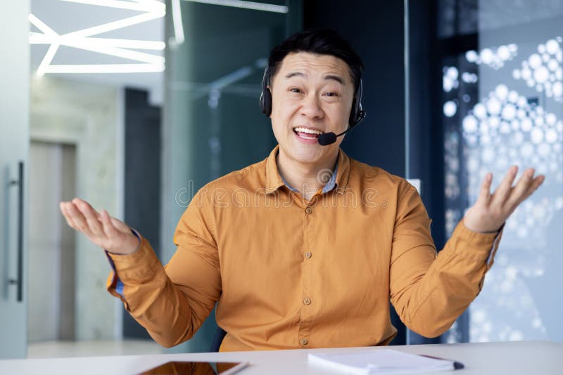 Asian Smiling Young Man Sitting in Office at Desk in Front of Camera ...