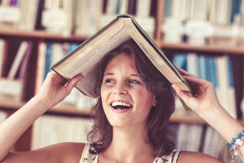 Cheerful Student Holding Book Over Her Head in Library Stock Photo ...