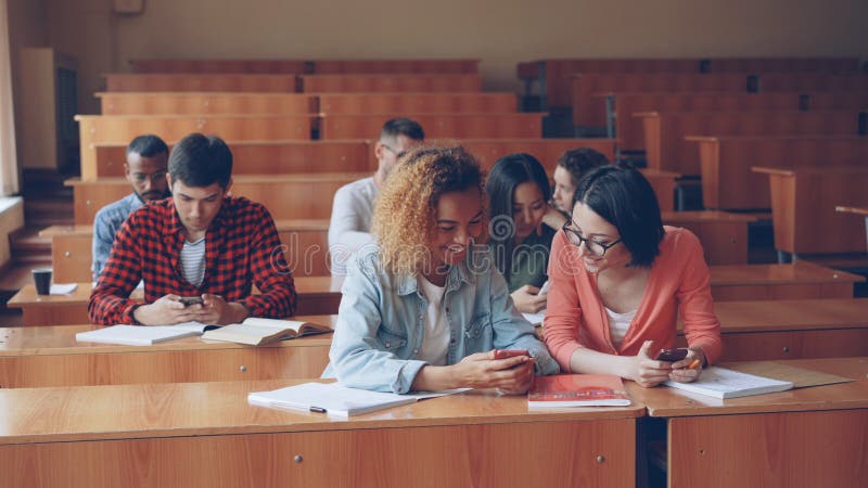 Cheerful Students are Using Smartphones and Chatting during Break ...