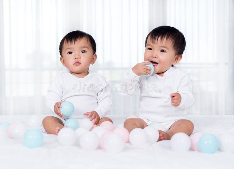 Cheerful Twin Babies Playing Color Ball on Bed Stock Photo - Image of ...