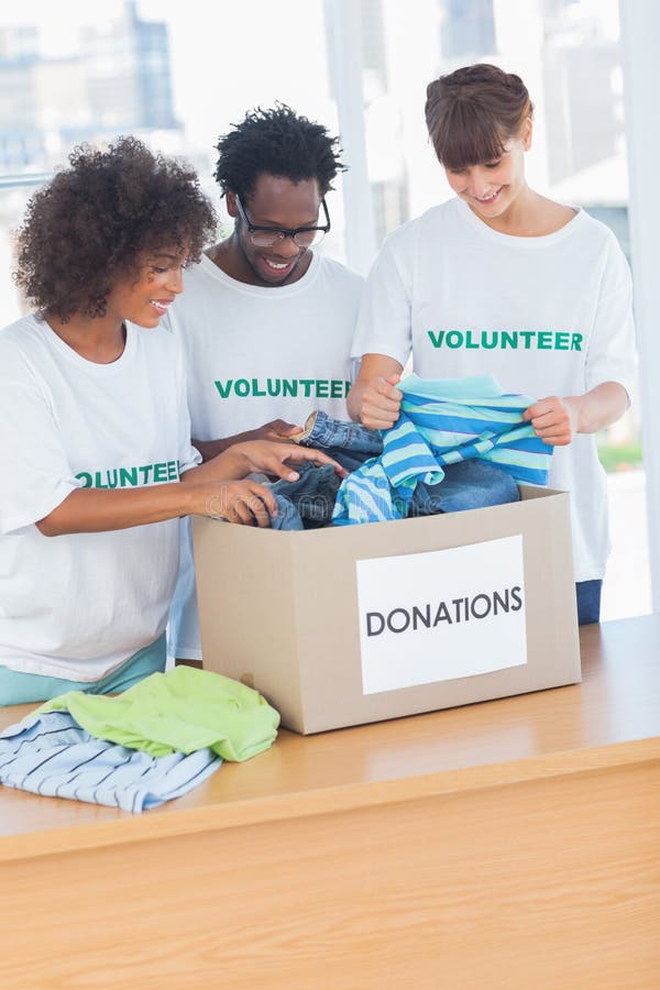 Cheerful Volunteers Looking at Clothes from a Donations Box Stock Photo ...