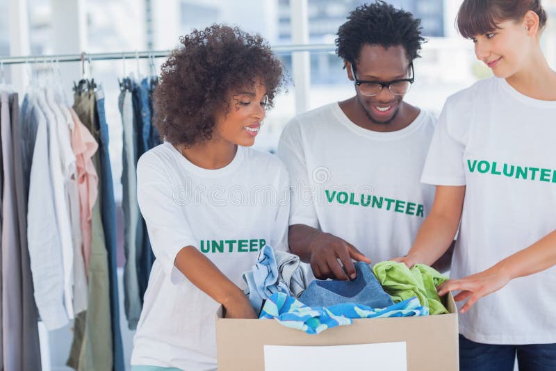 Cheerful Volunteers Taking Out Clothes from a Donation Box Stock Image ...