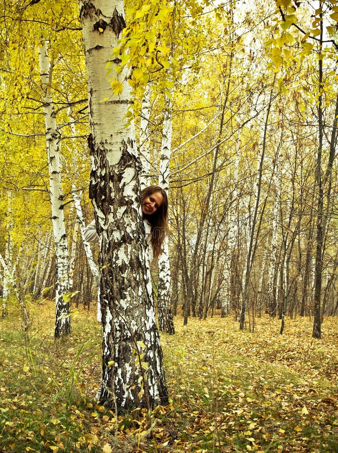 Cheerful Woman Looks Out from Behind a Tree Stock Photo - Image of ...