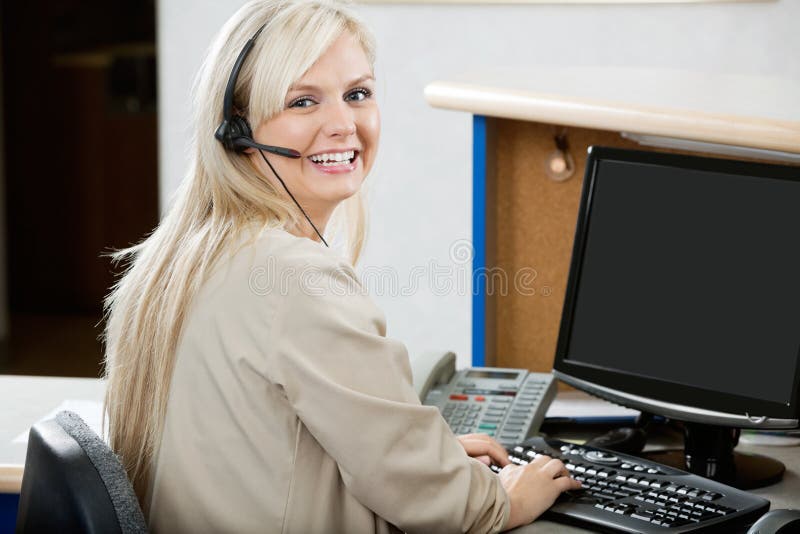 Cheerful Woman Using Computer at Reception Desk Stock Photo - Image of ...