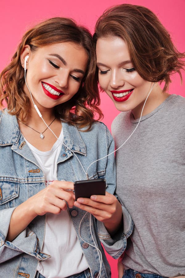 Cheerful Women Friends Using Mobile Phone Listening Music. Stock Image ... Cheerful Women Friends Using Mobile Phone Listening Music. Stock Image ...