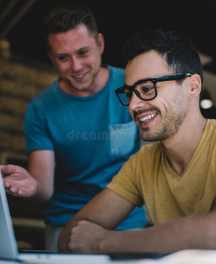 Cheerful Young Male Colleagues Working on Business Project in Cafe ...
