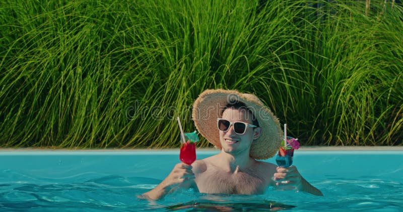Cheerful Young Man Dancing in the Pool with Two Cocktails in His Hands ...