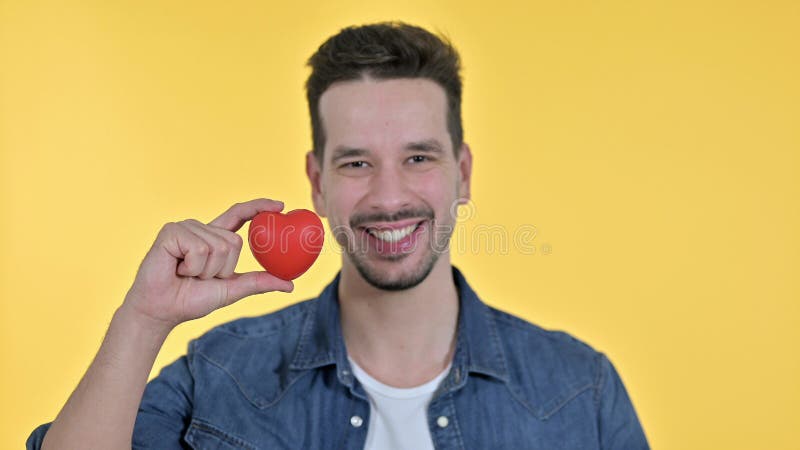Cheerful Young Man Holding Heart Shape, Yellow Background Stock Photo ...