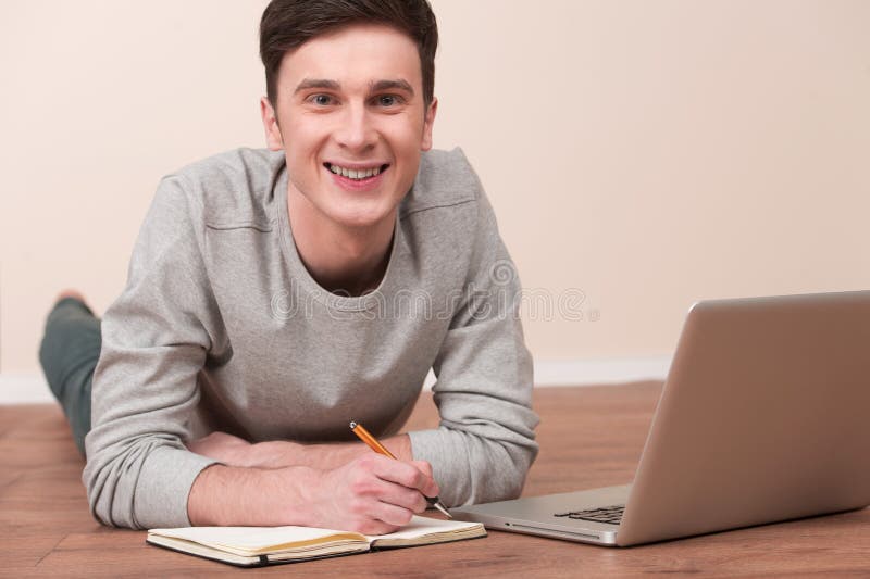 Cheerful Young Man Lying on Floor with Notebook. Stock Image - Image of ...