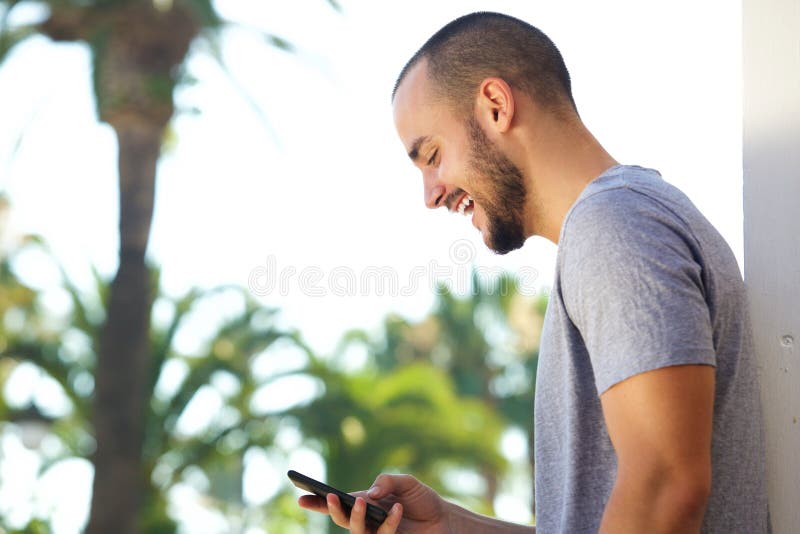 Cheerful Young Man Reading Text Message on Mobile Phone Stock Photo ...