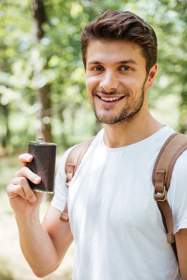 Cheerful Young Man Standing and Holding Flask in Forest Stock Image ...