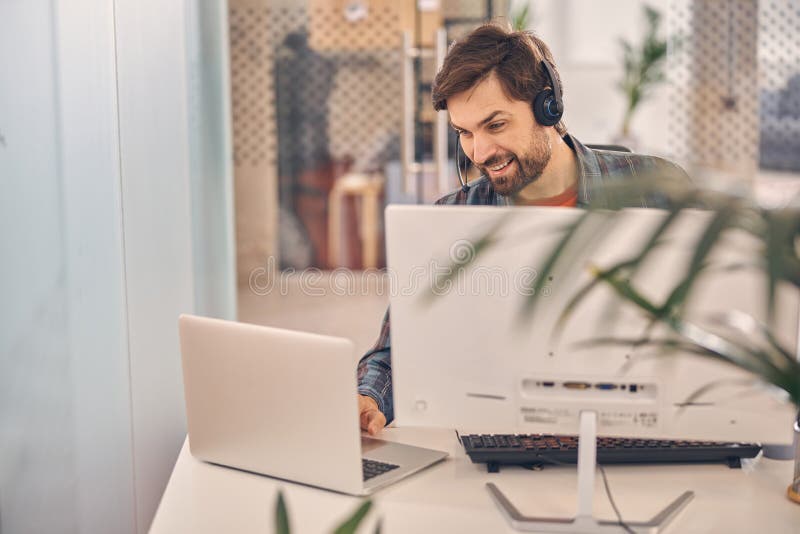 Cheerful Young Man Using Computer and Laptop at Work Stock Photo ...