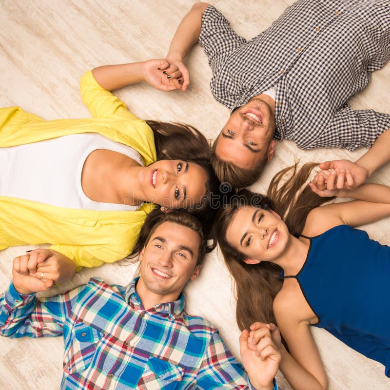Cheerful Young People Lying on the Floor Holding Hands Stock Photo ...
