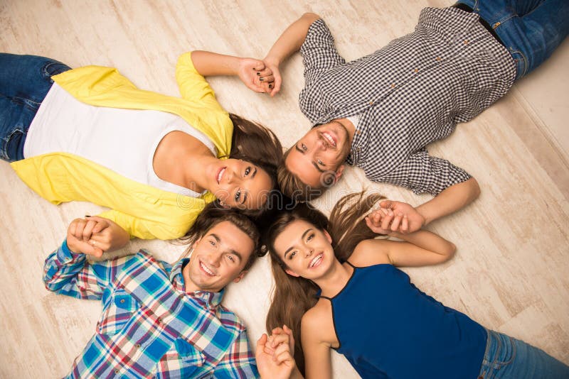 Cheerful Young People Lying on the Floor Holding Hands Stock Photo ...