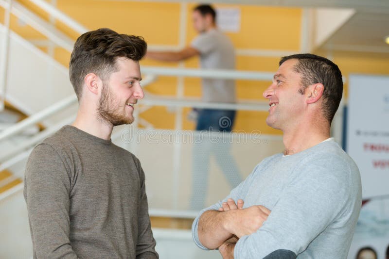 Cheery Guys Chatting Next To Stairway Stock Photo - Image of foreground ...