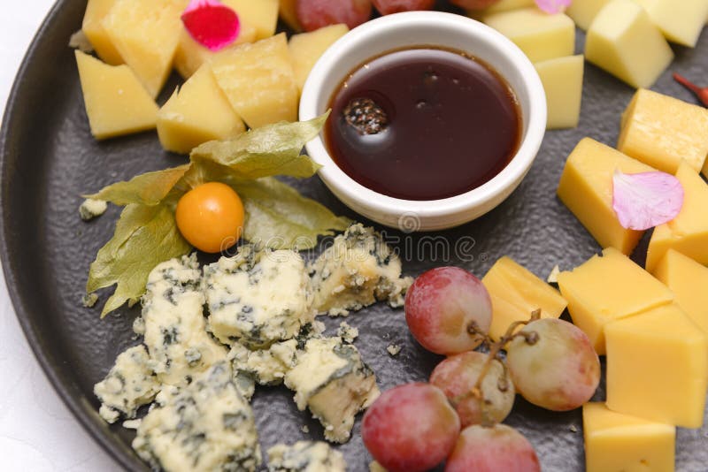 Cheese Plate with Different Cheese Slices, Grapes, Honey Stock Photo ...