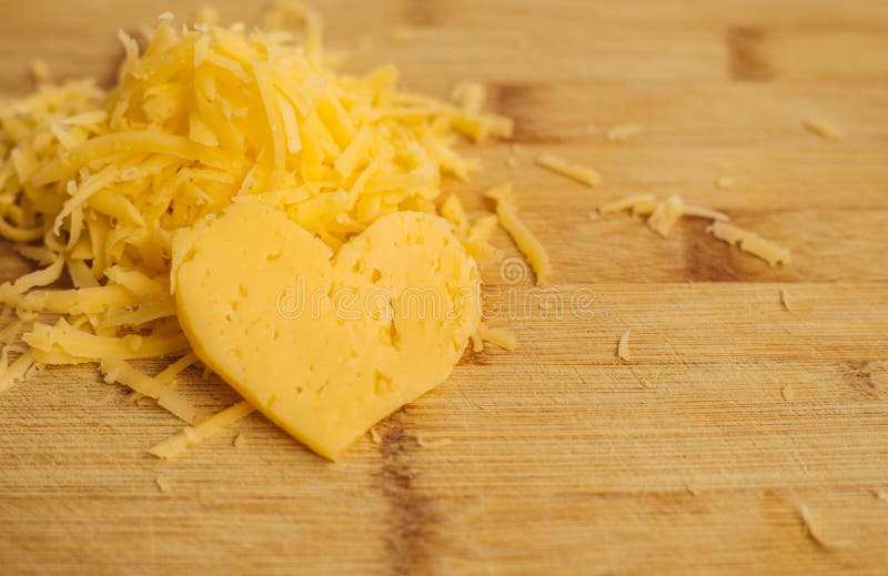 Cheese in the Shape of a Heart on a Wooden Board. Grated Cheese in the ...