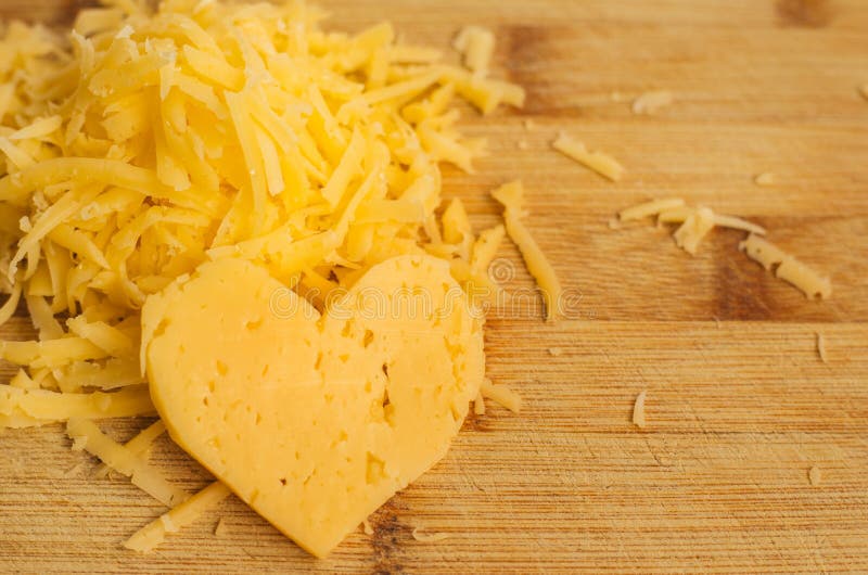 Cheese in the Shape of a Heart on a Wooden Board. Grated Cheese in the ...