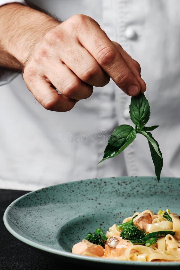 Chef adding basil to pasta stock photo. Image of plate - 169699590
